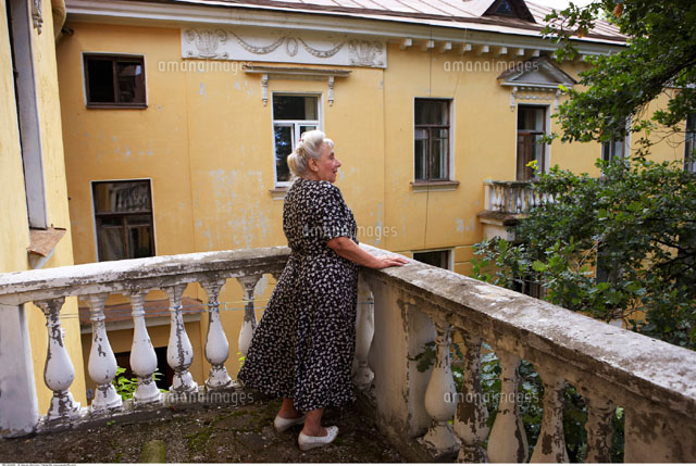Woman Looking Over Balcony[20025182393]の写真素材・イラスト素材｜アマナイメージズ