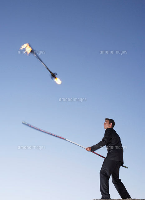 Man Standing on Rock Fending Off[20025227300]の写真素材・イラスト素材｜アマナイメージズ