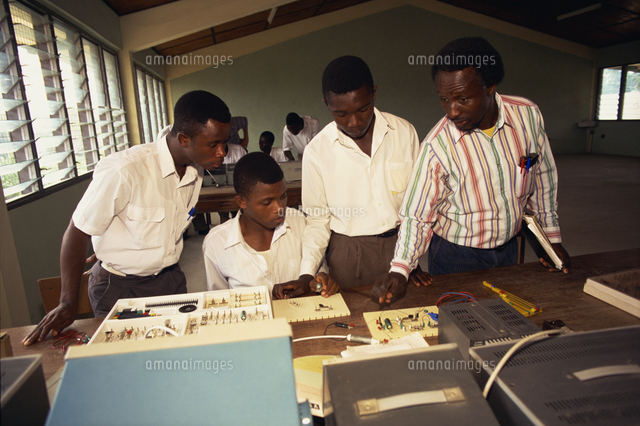 Teacher with three teenage students taking a science lesson in a school ...