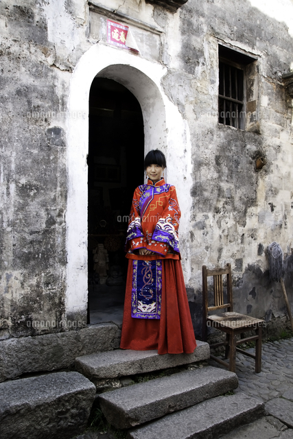 Young bride in red traditional Chinese bridal dress outside her ancient ...