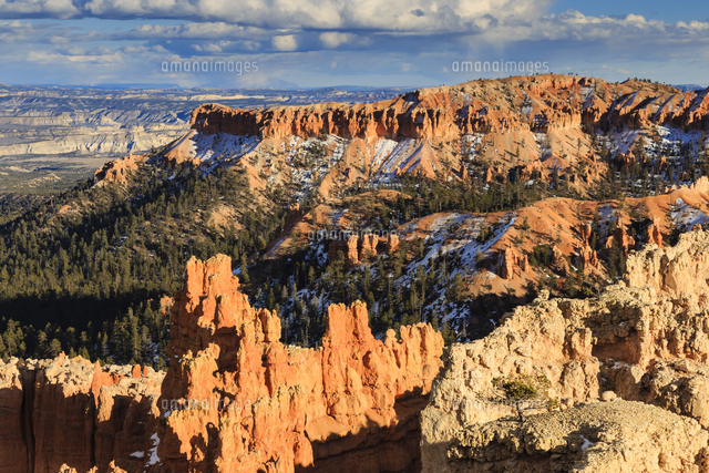 Late afternoon sun lights hoodoos and rocks through a cloudy sky in ...