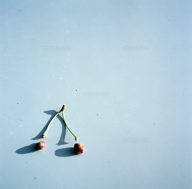 Eaten cherries on blue surface, leaving shadow looking like the ...