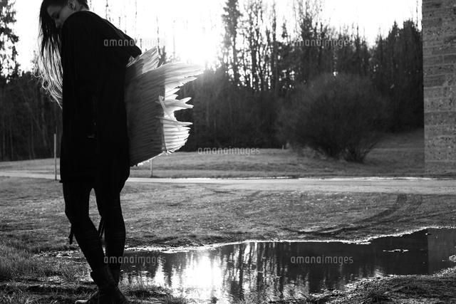 Young woman carrying white angel wings under her arm standing next to ...