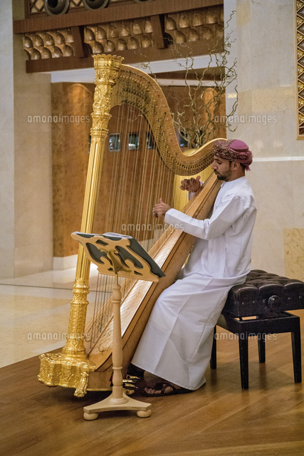 Oman, Muscat. An Omani musician playing a harp at the Al Bustan Palace ...