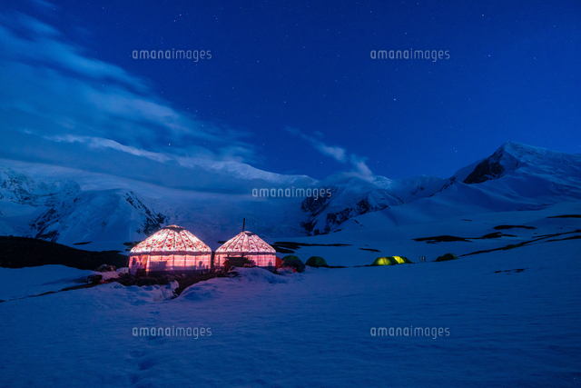 The yurts and tents of peak Lenin camp one illuminated at dusk with ...
