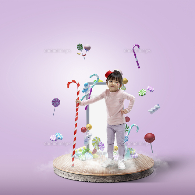 Smiling girl posing with candy cane[20090003975]の写真素材・イラスト素材｜アマナイメージズ