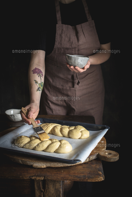 Challah bread (Jewish cuisine) being made: yeast plait being brushed ...