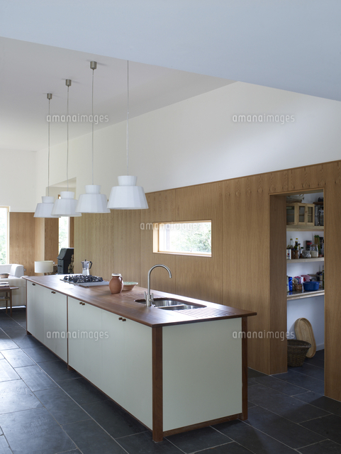 Kitchen area with sink and hob with wooden panelled walls and hanging ...