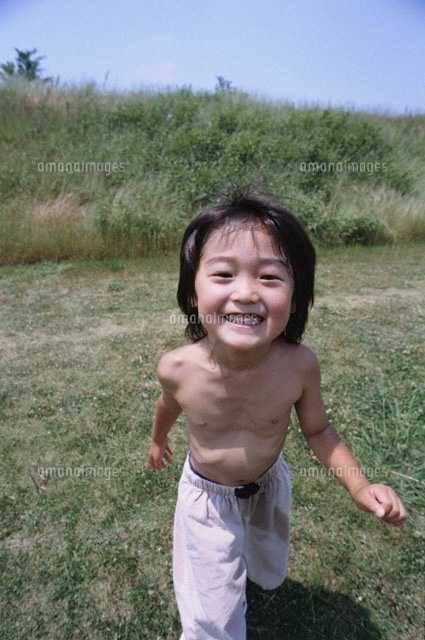 土手で笑う日本人の男の子[02148010471]の写真素材・イラスト素材｜アマナイメージズ