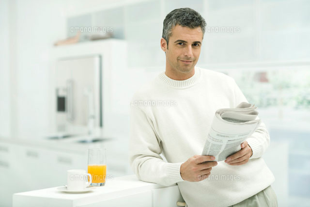 Man leaning against kitchen counter，holding newspaper[11001045946]の写真素材 ...
