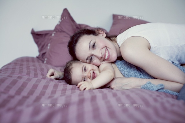 Mother and infant lying on bed[11001052813]の写真素材・イラスト素材｜アマナイメージズ