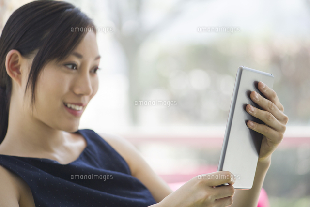 Woman relaxing with digital tablet[11001060619]の写真素材・イラスト素材｜アマナイメージズ