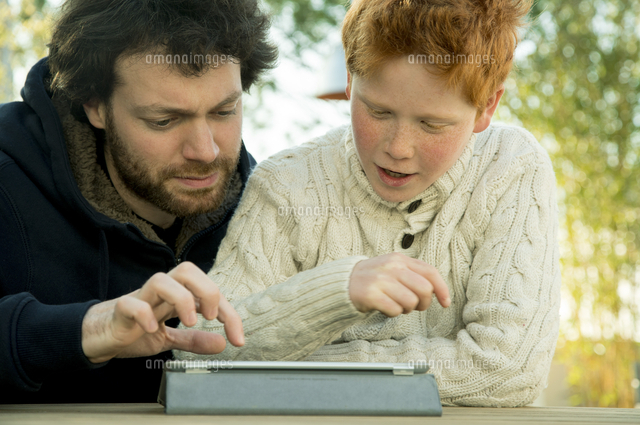 Father and son looking at digital tablet together[11001062525]の写真素材 ...
