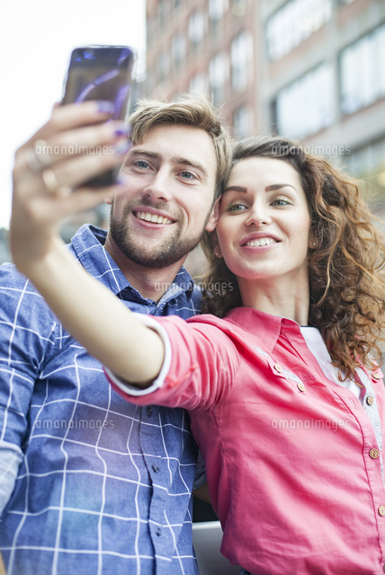 Couple Taking A Selfie Together Outdoors[11001065237]の写真素材・イラスト素材｜アマナイメージズ