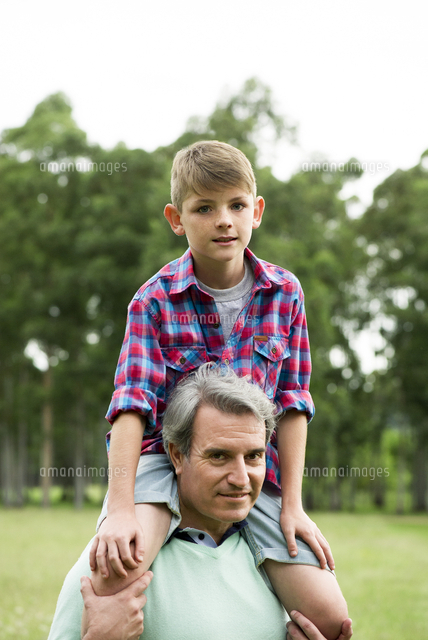 Father carrying son on shoulders, portrait[11001066527]の写真素材・イラスト素材｜アマナ ...