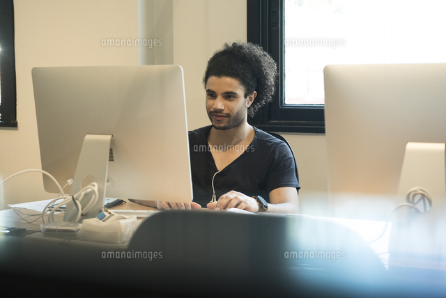 Young man using desktop computer[11001067247]の写真素材・イラスト素材｜アマナイメージズ