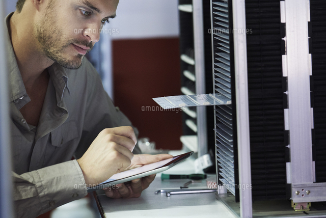 Close-up of engineer looking at chip in office[11001069255]の写真素材・イラスト素材 ...