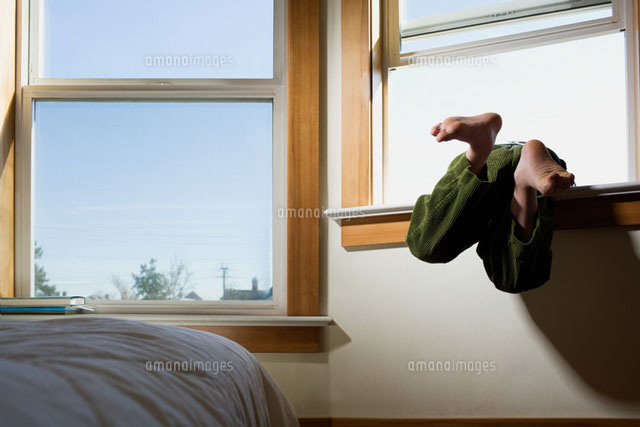 Boy climbing out of window[11015183886]の写真素材・イラスト素材｜アマナイメージズ
