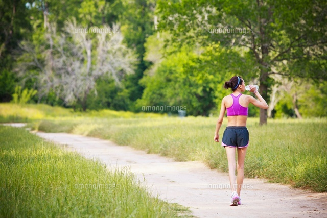 Young woman walking on path drinking mineral water[11015206888]の写真素材 ...