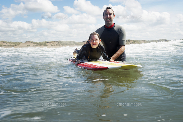 Father and daughter surfing in the sea[11015219529]の写真素材・イラスト素材｜アマナイメージズ