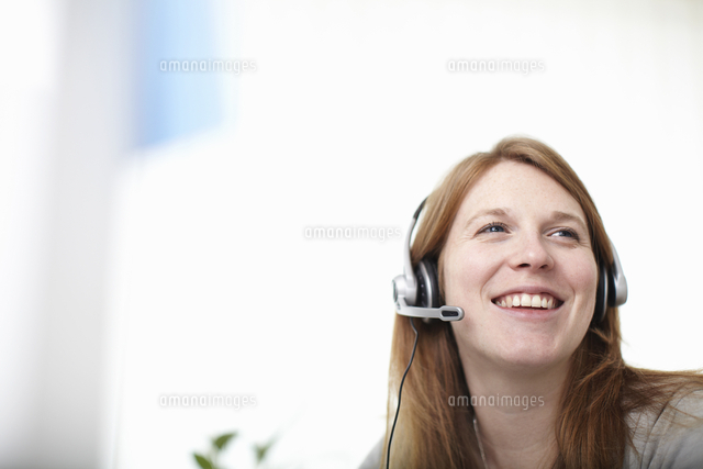Happy girl with headset next to computer[11015220568]の写真素材・イラスト素材｜アマナイメージズ