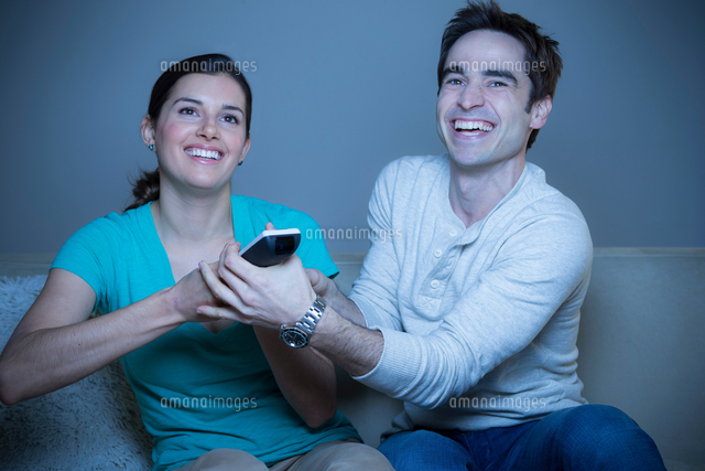 Couple watching television, fighting over remote control[11015231035]の ...