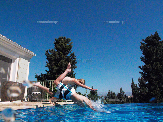 Girl and teenage brother diving into apartment swimming pool ...