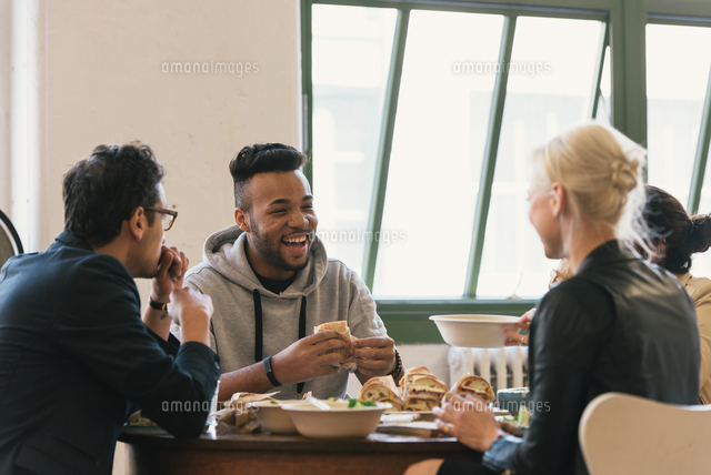 Colleagues in office sharing lunch[11015285238]の写真素材・イラスト素材｜アマナイメージズ