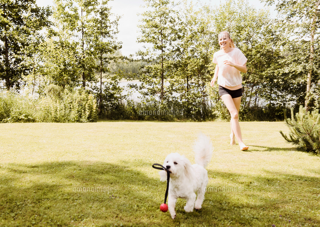 Woman running after coton de tulear dog in garden, Orivesi, Finland ...
