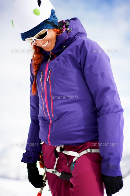 Woman wearing safety harness and climbing helmet looking down smiling ...