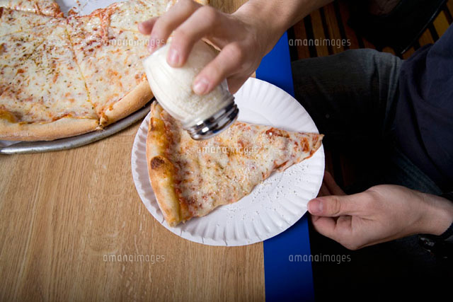Person pouring salt onto pizza[11016012749]の写真素材・イラスト素材｜アマナイメージズ