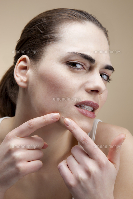 A young woman frowning in concentration as she squeezes a pi ...