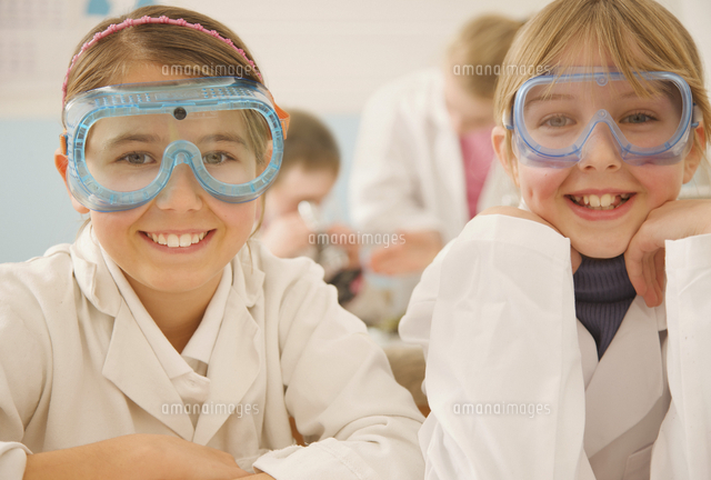 Portrait smiling junior high school girl students in science goggles ...