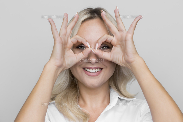 Portrait playful woman gesturing finger goggles[11016044647]の写真素材・イラスト ...
