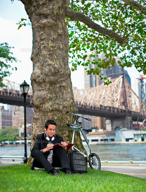 Businessman Making Notes Under Tree[11021007949]の写真素材・イラスト素材｜アマナイメージズ