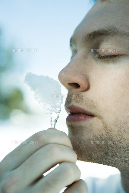 Young man smelling piece of snow[11025002085]の写真素材・イラスト素材｜アマナイメージズ