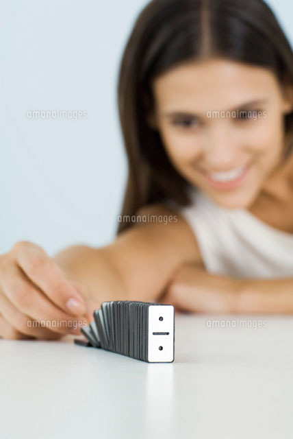 Woman setting off domino chain reaction[11025005426]の写真素材・イラスト素材｜アマナイメージズ