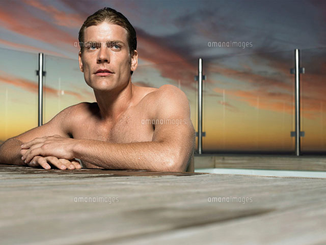 Man leaning on edge of outdoor pool at sunset[11044006143]の写真素材・イラスト素材 ...