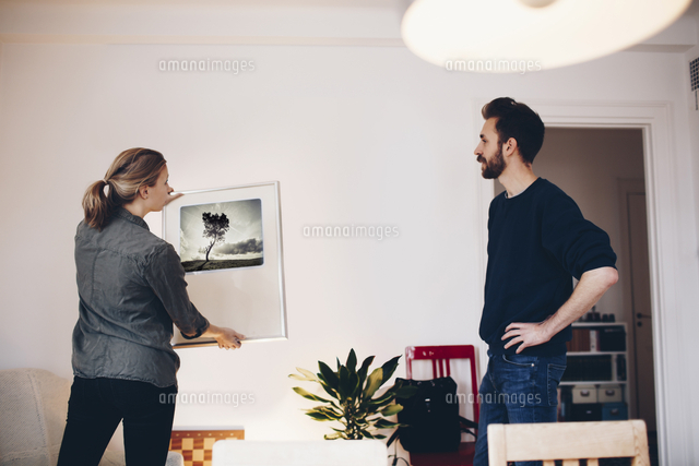 Man and woman discussing painting at home[11081016478]の写真素材・イラスト素材｜アマナイメージズ