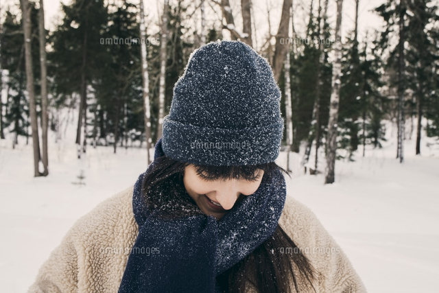 Smiling mid adult woman wearing knit hat and scarf during winter ...