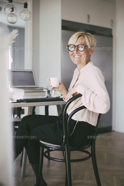 Portrait of smiling woman working at home[11081031211]の写真素材・イラスト素材｜アマナイメージズ