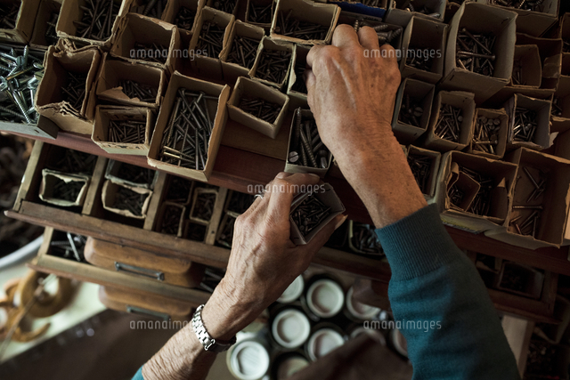 Directly above view of senior female sales clerk removing nails from ...