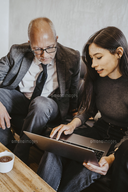 Young female programmer discussing over laptop with male advisor at ...