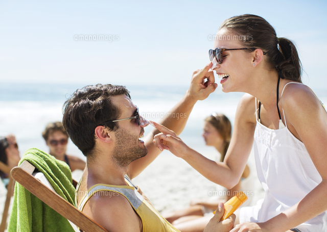 Couple applying sunscreen to each other's nose on beach[11086006069]の写真 ...