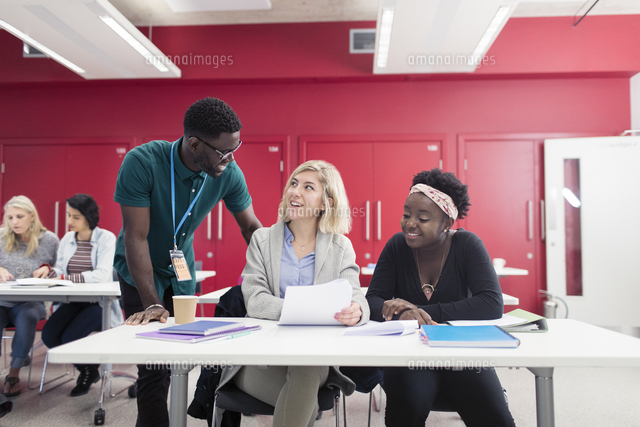 Community college instructor helping students with paperwork in ...