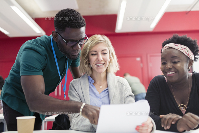 Community college instructor helping students with paperwork in ...