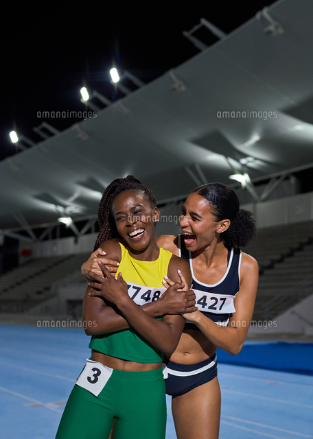Happy female track and field athletes hugging after competition ...