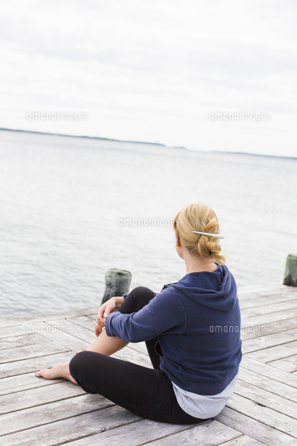 Sweden, Stockholm Archipelago, Grasko, Woman sitting on jetty ...