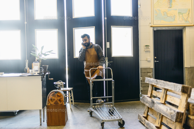 A coffee roaster talking on a cell phone and pushing a trolley in ...