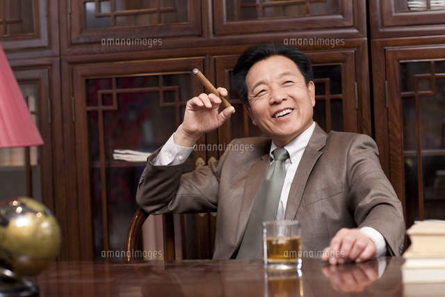 Successful businessman enjoying cigar[11091002683]の写真素材・イラスト素材｜アマナイメージズ